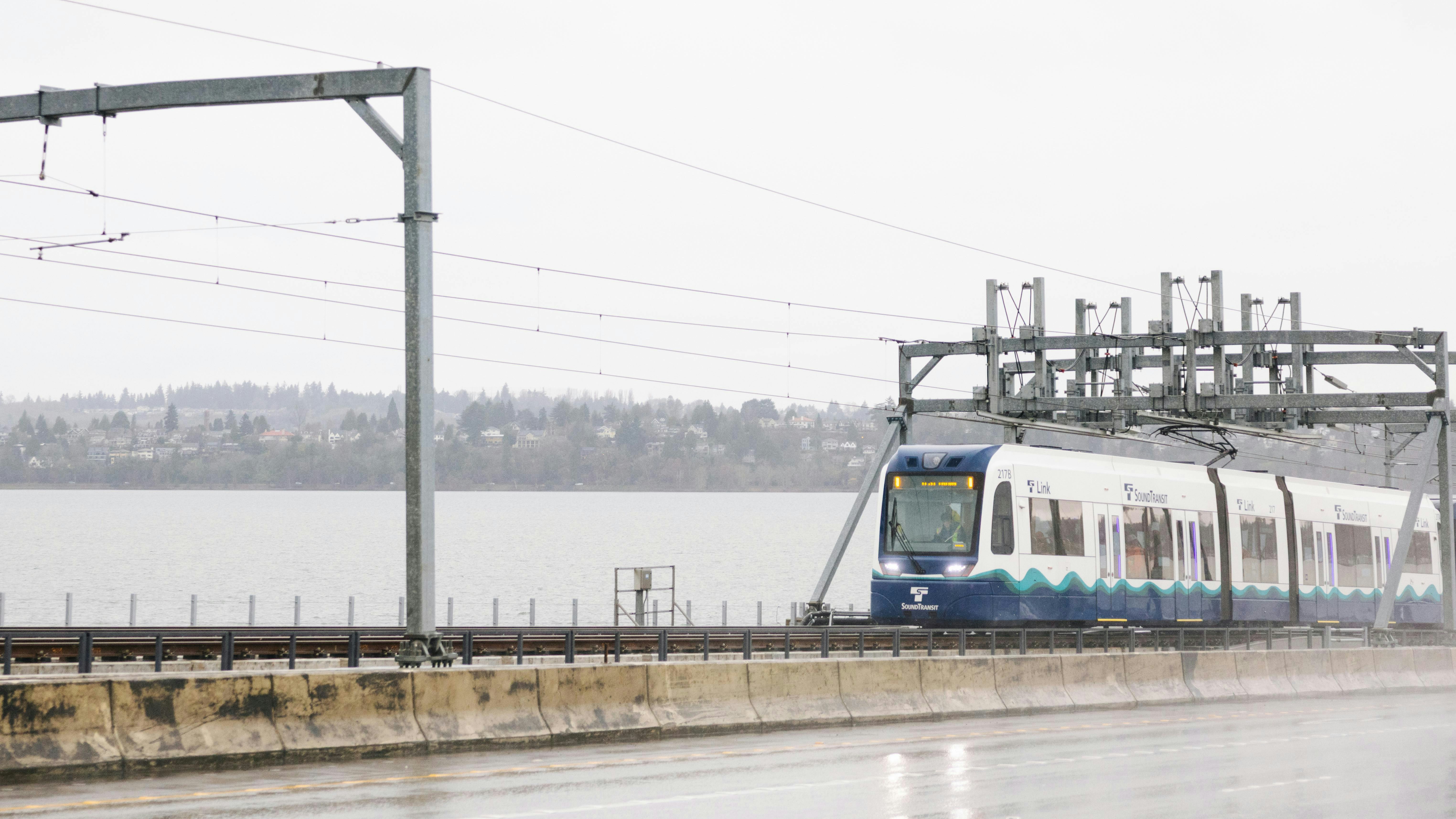 A Sound Transit light-rail vehicle crosses water on a floating bridge.
